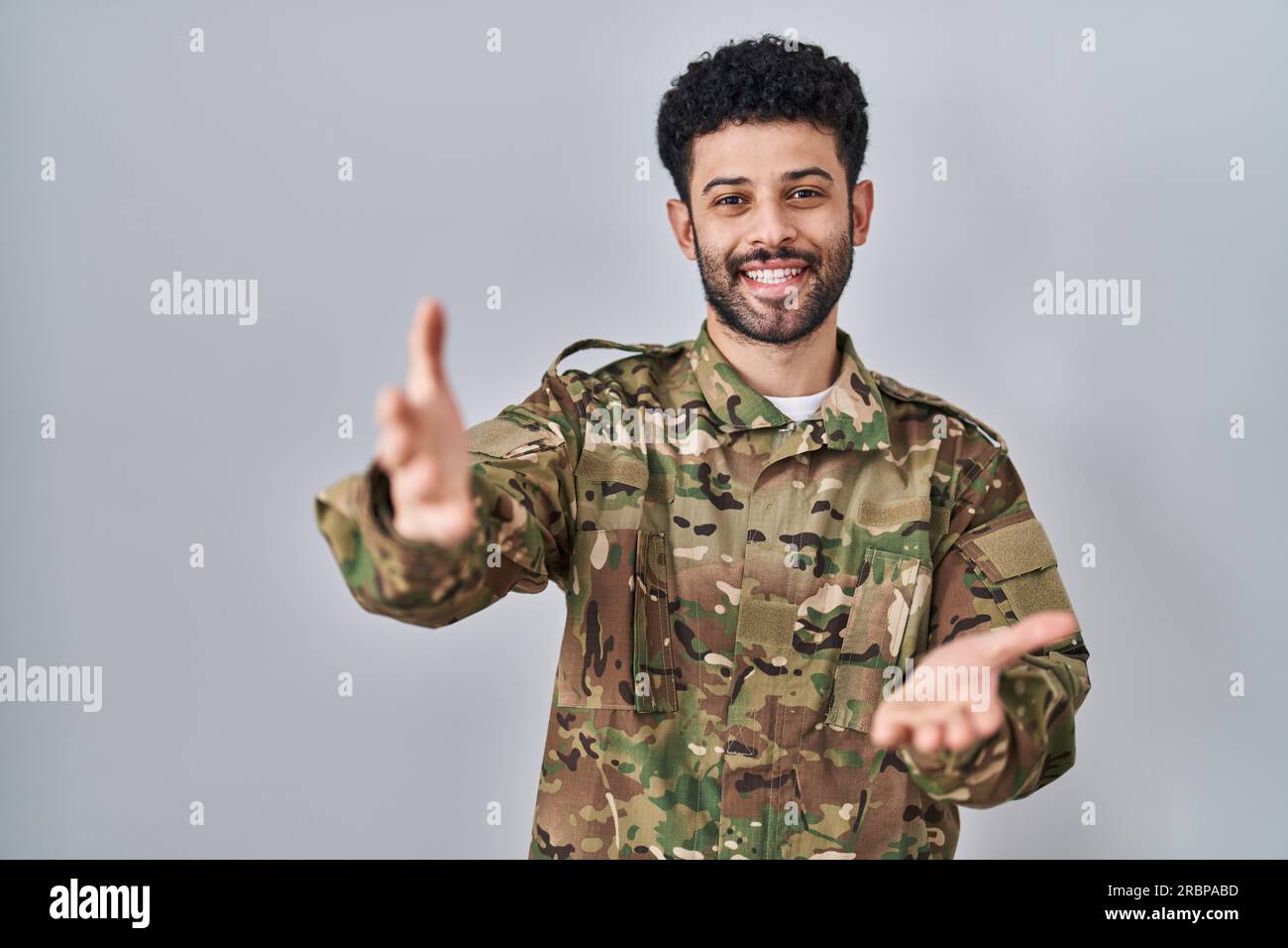 Arab man wearing camouflage army uniform smiling cheerful offering ...