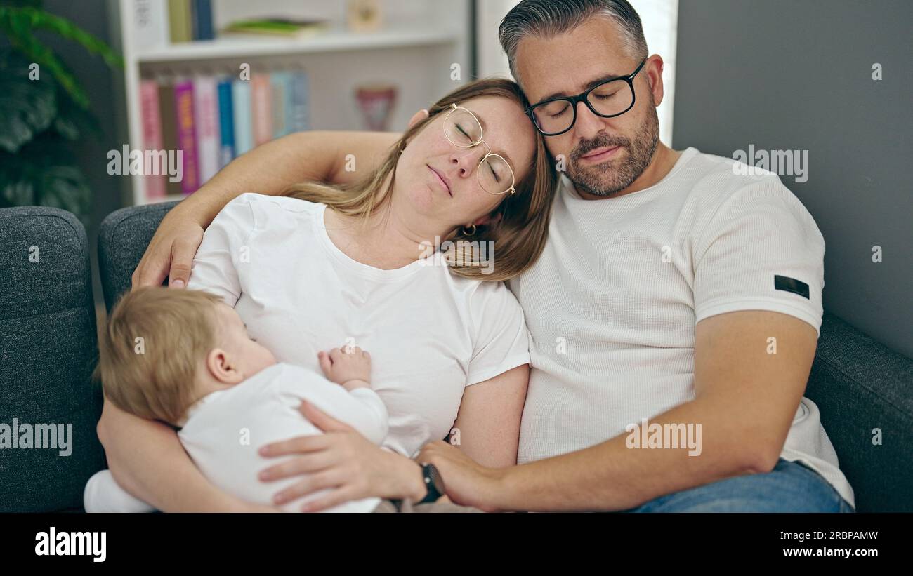 Family of mother, father and baby resting sitting on the sofa at home ...