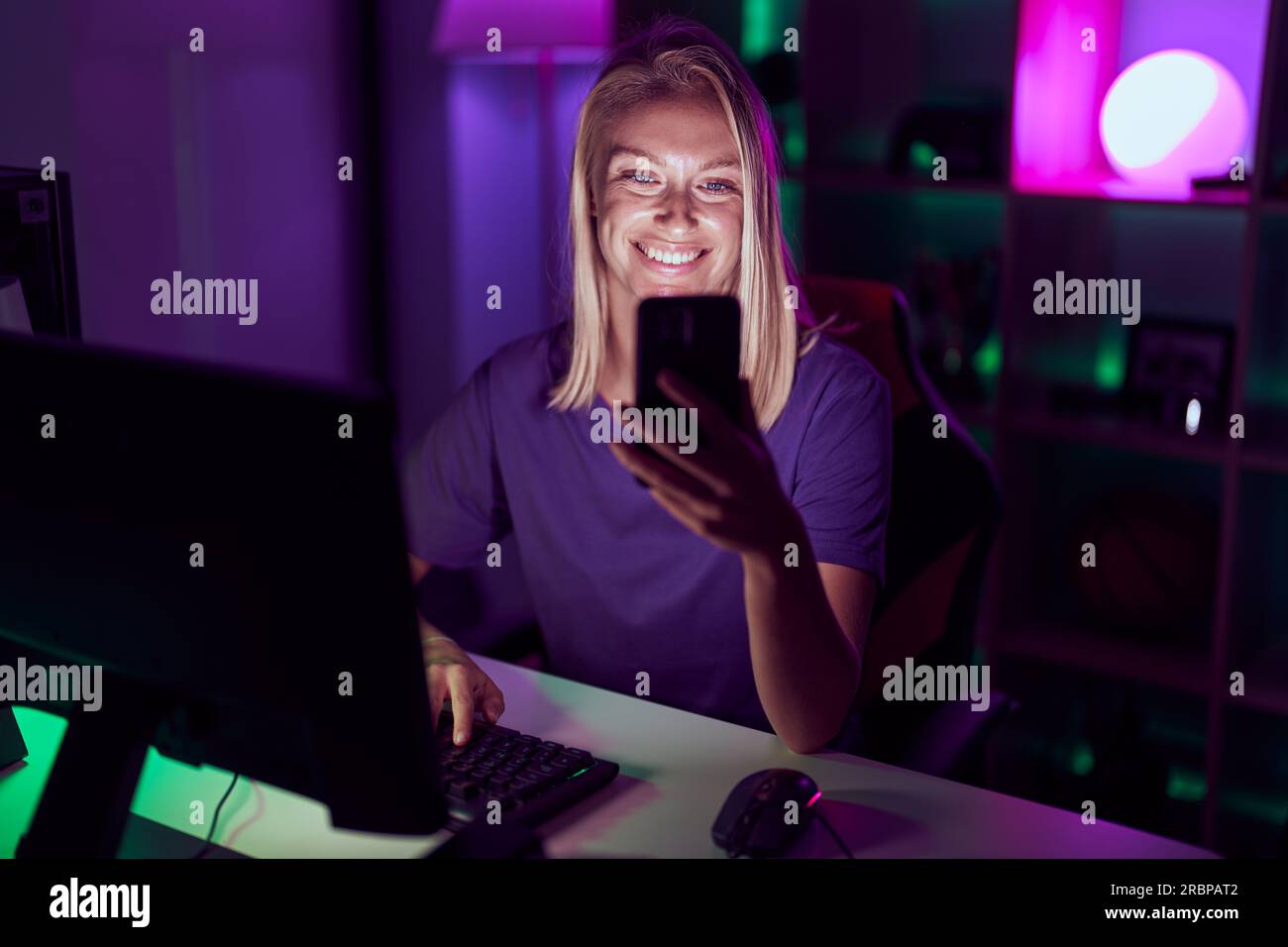 Young blonde woman streamer using computer and smarpthone at gaming ...