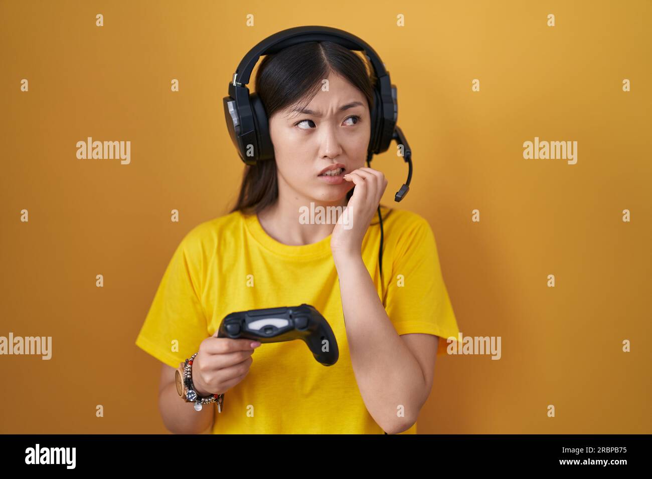 Chinese young woman playing video game holding controller looking ...