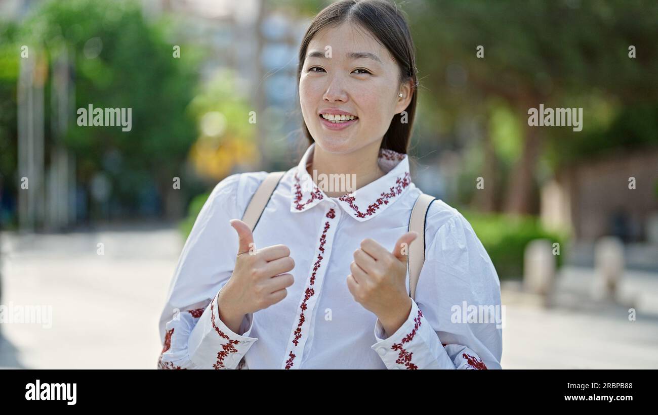 Young chinese woman smiling confident doing ok sign with thumbs up at ...