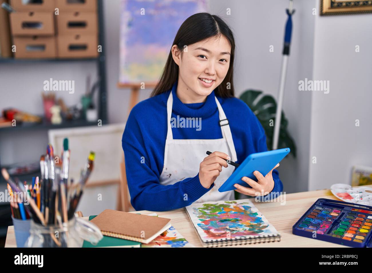 Chinese woman artist using touchpad drawing on notebook at art studio ...