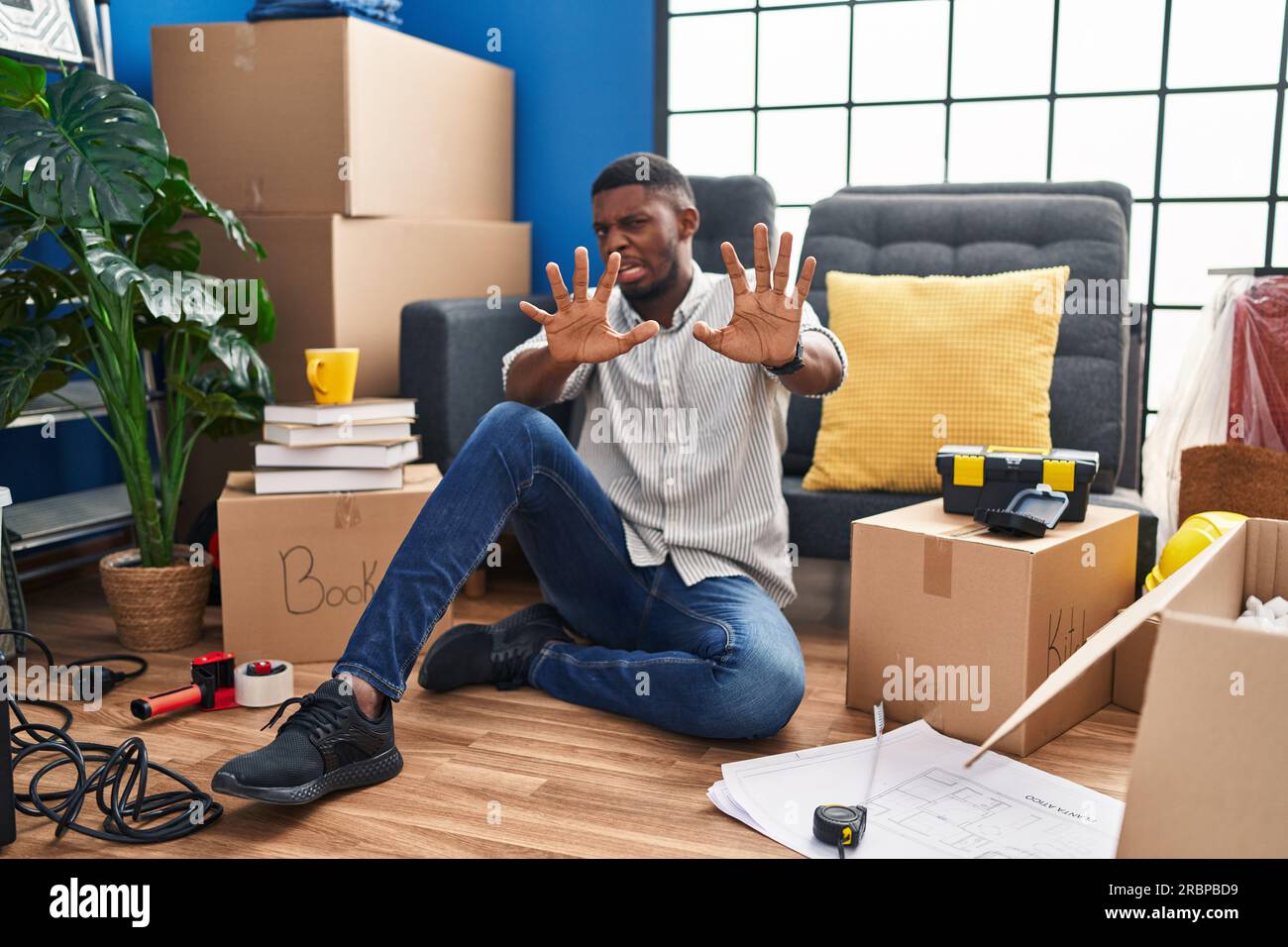 African american man sitting on the floor at new home afraid and ...