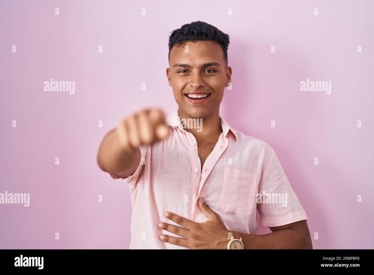 Young Hispanic Man Standing Over Pink Background Laughing At You Pointing Finger To The Camera