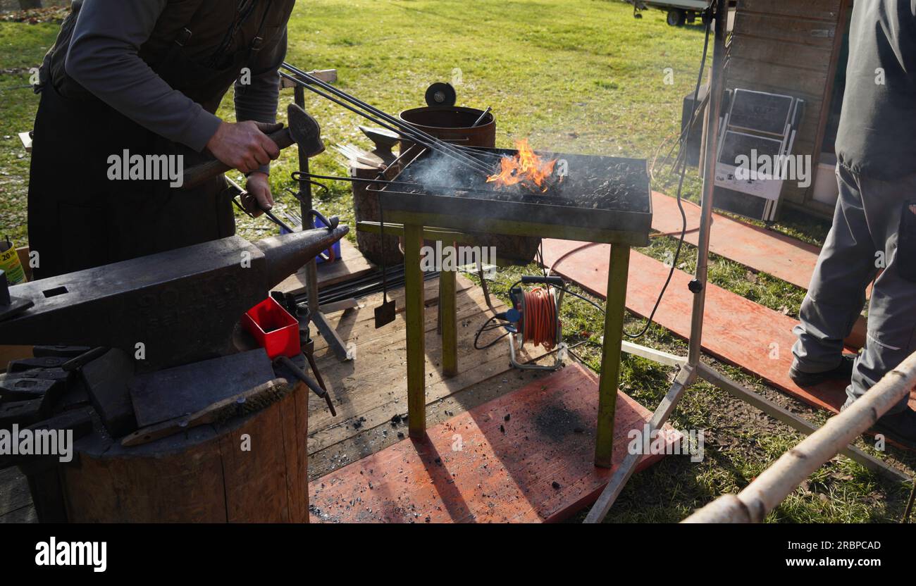 Blacksmith with red-hot iron and open charcoal fire at work Stock Photo ...