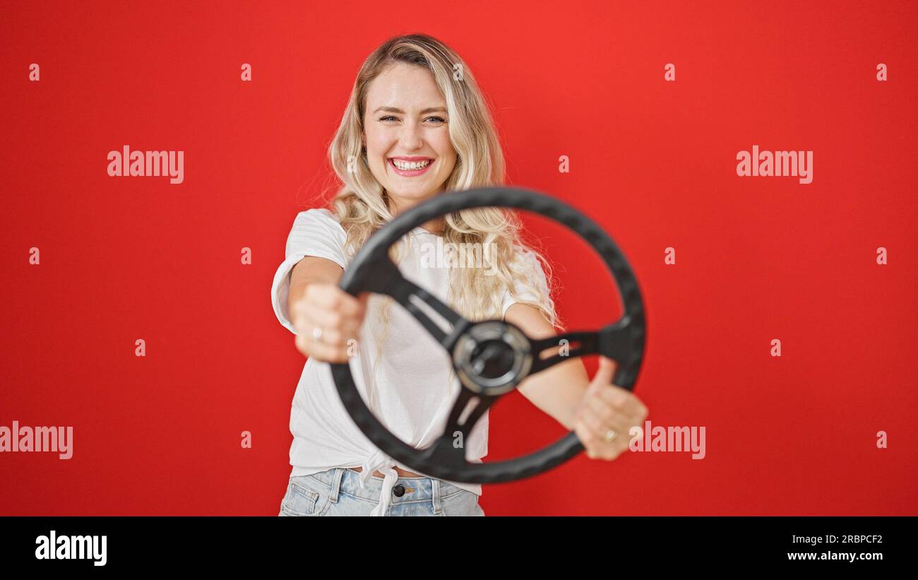 Young blonde woman smiling confident using steering wheel as a driver ...