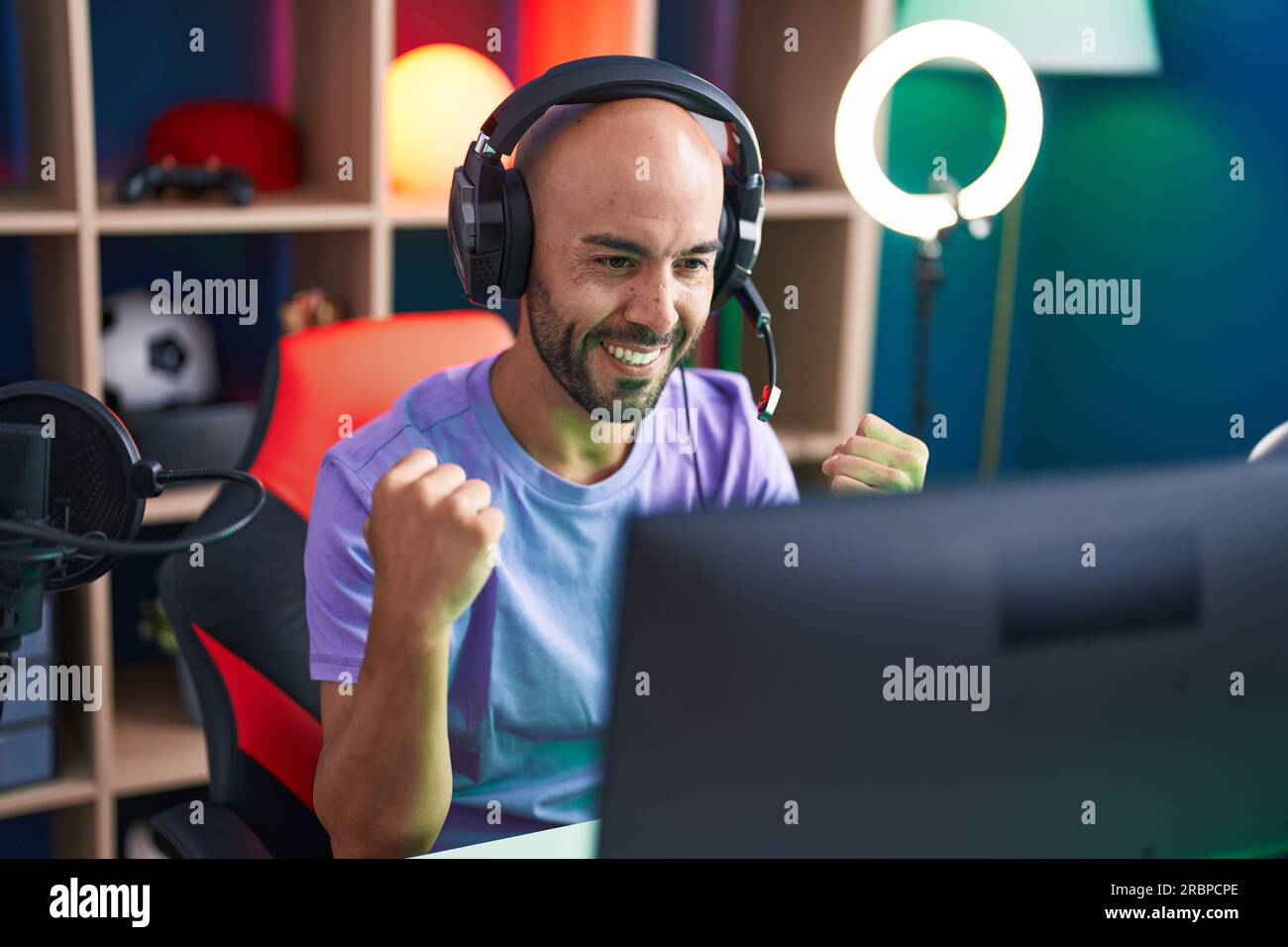 Young bald man streamer playing video game with winner expression at ...
