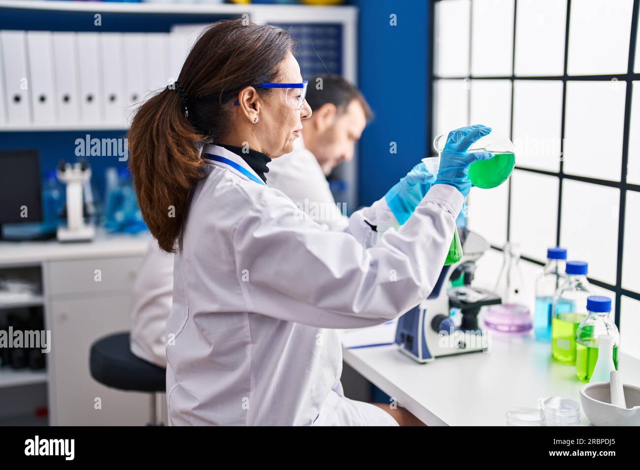 Middle age man and woman scientists measuring liquid at laboratory ...