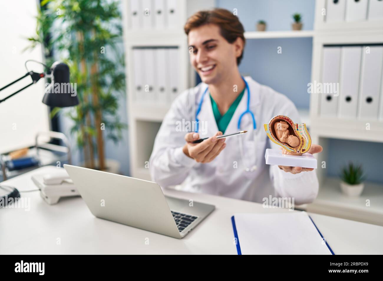 Young caucasian man doctor holding anatomical model of uterus with ...