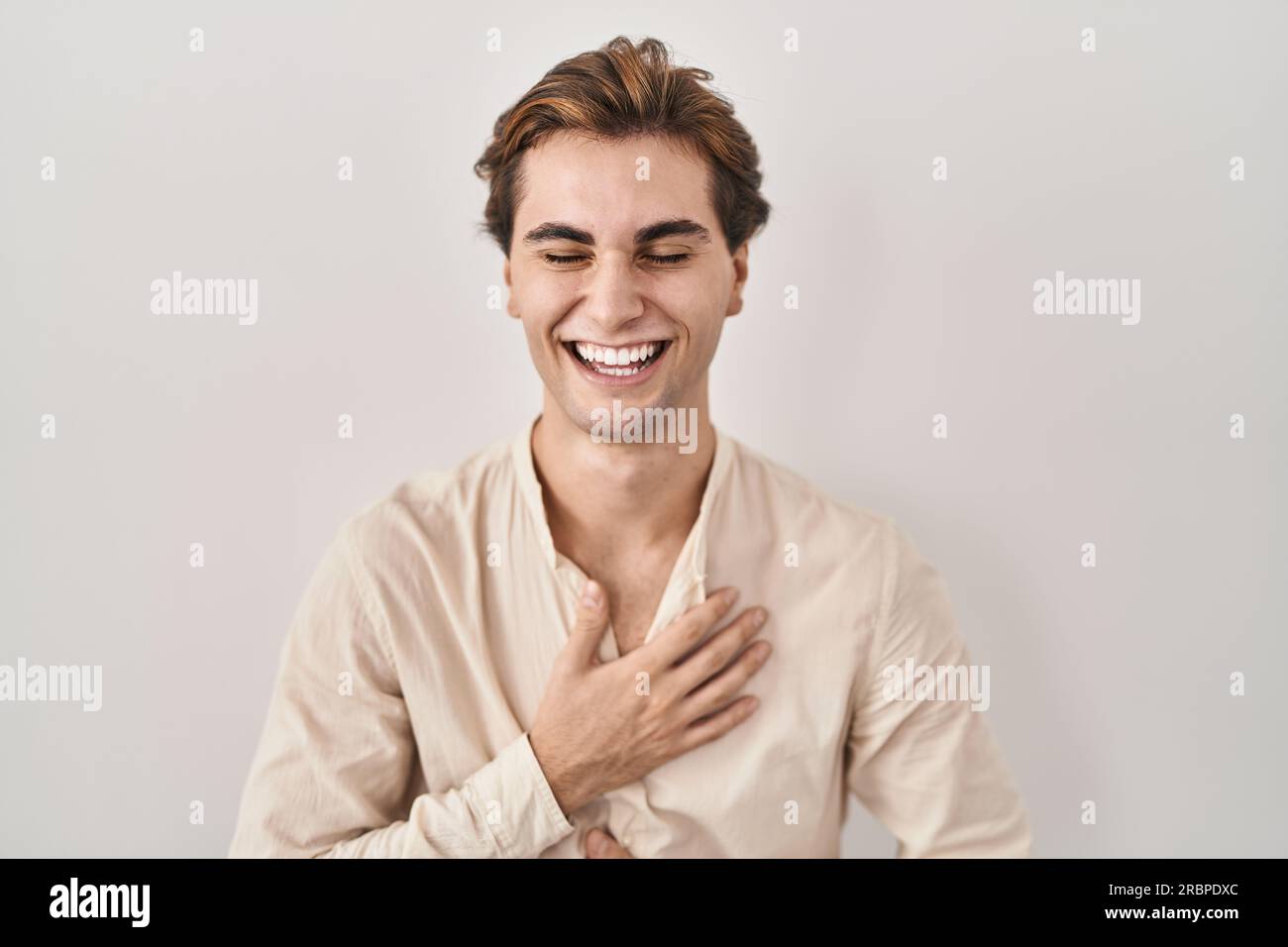Young man standing over isolated background smiling and laughing hard ...