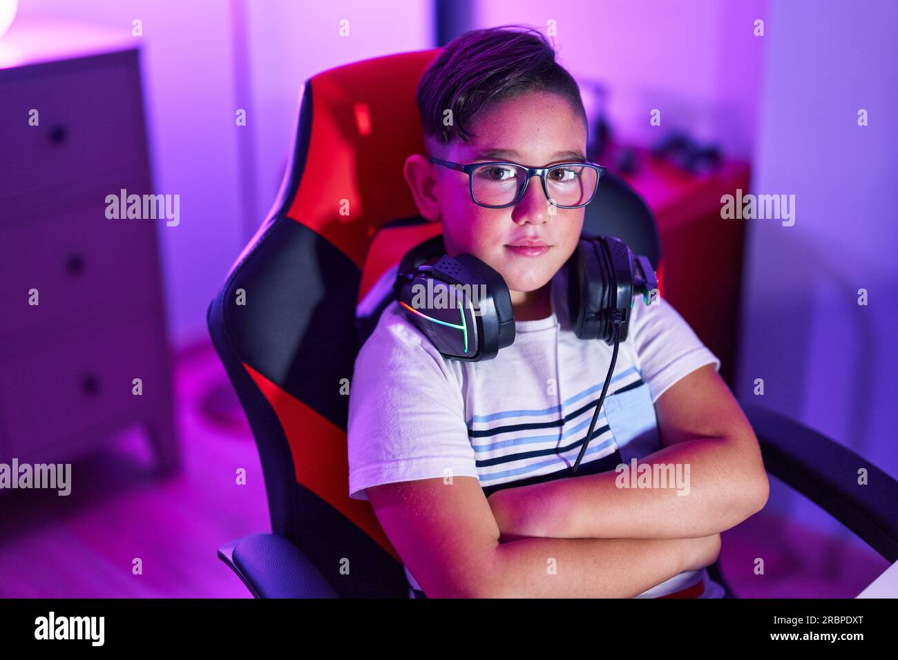 Adorable hispanic boy streamer sitting with arms crossed gesture at ...
