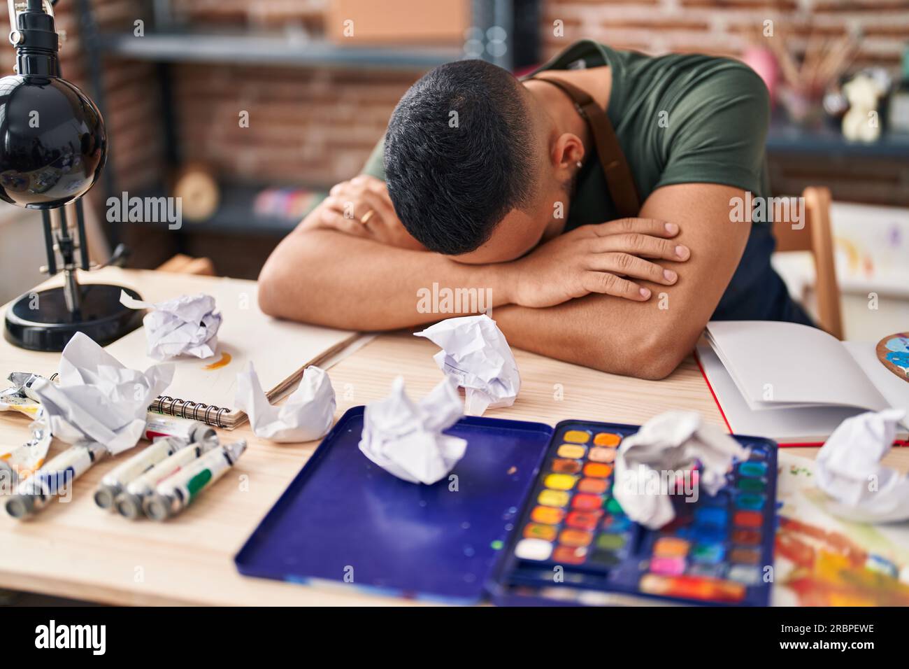 African american man artist stressed sitting on table at art studio ...