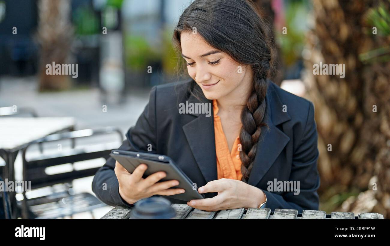 Young beautiful hispanic woman business worker using touchpad sitting ...