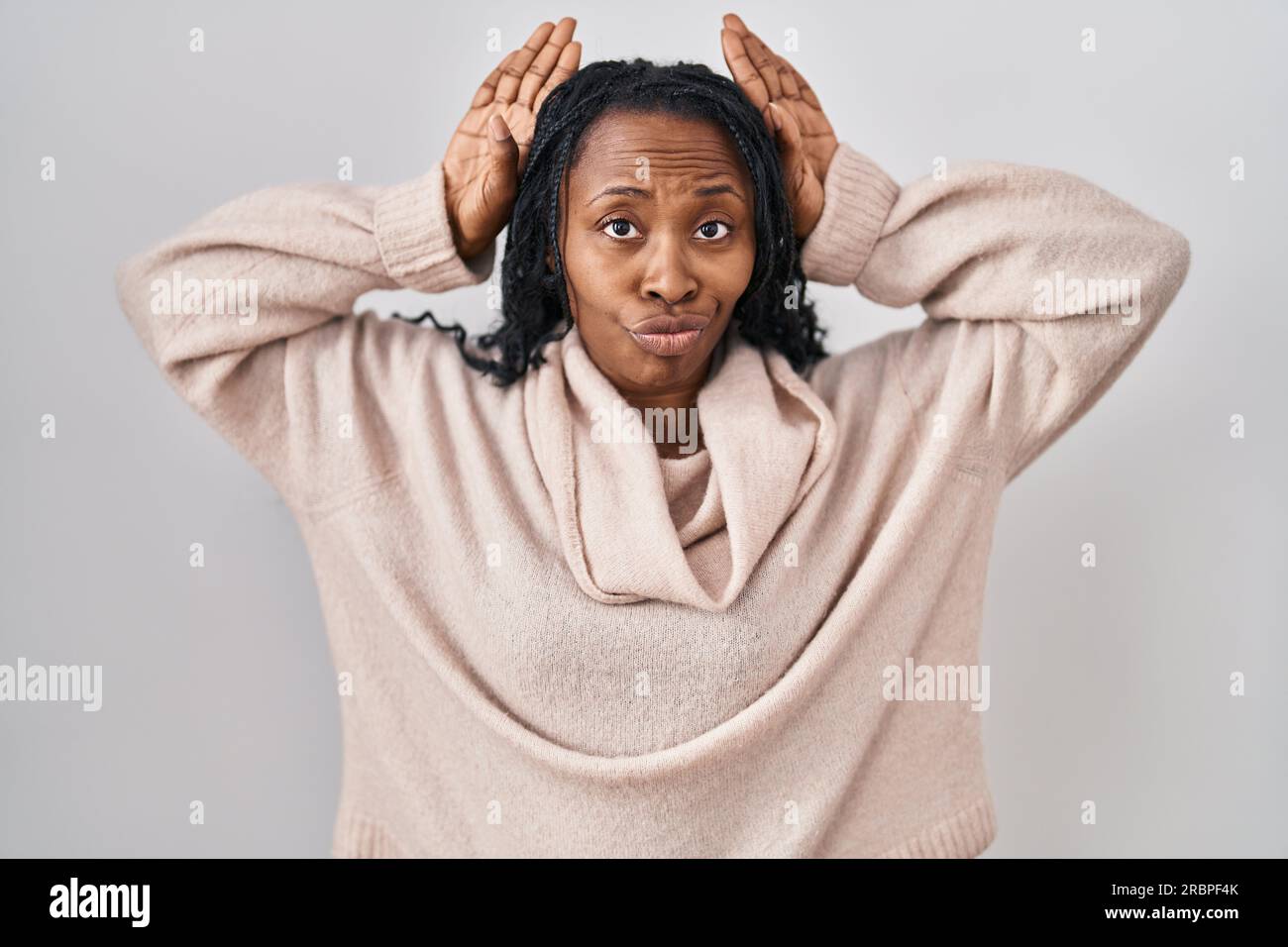 African woman standing over white background doing bunny ears gesture ...