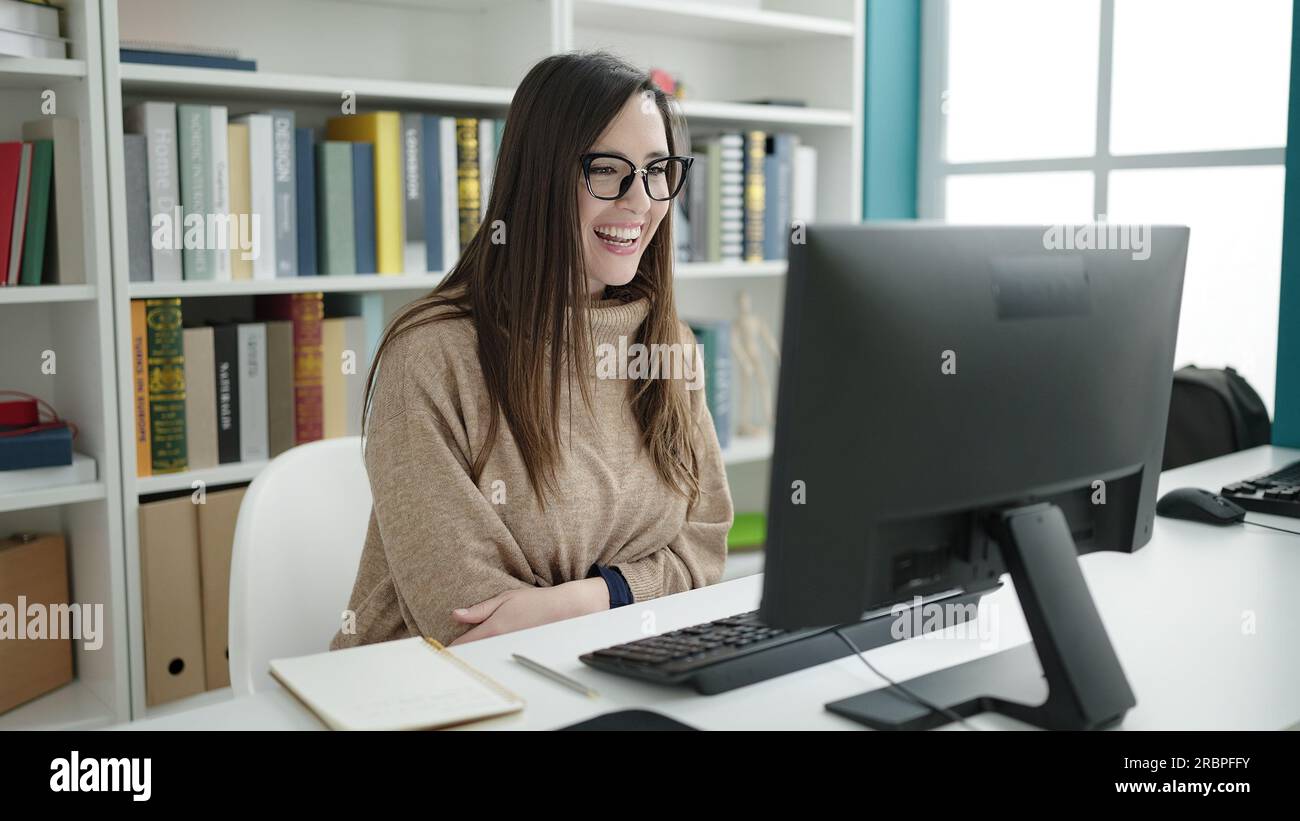Beautiful hispanic woman student using computer studying at library ...