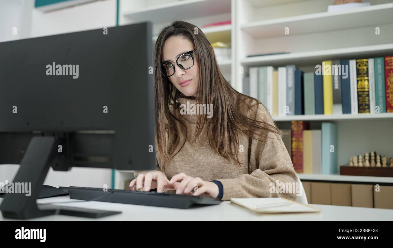 Beautiful hispanic woman student using computer studying at library ...