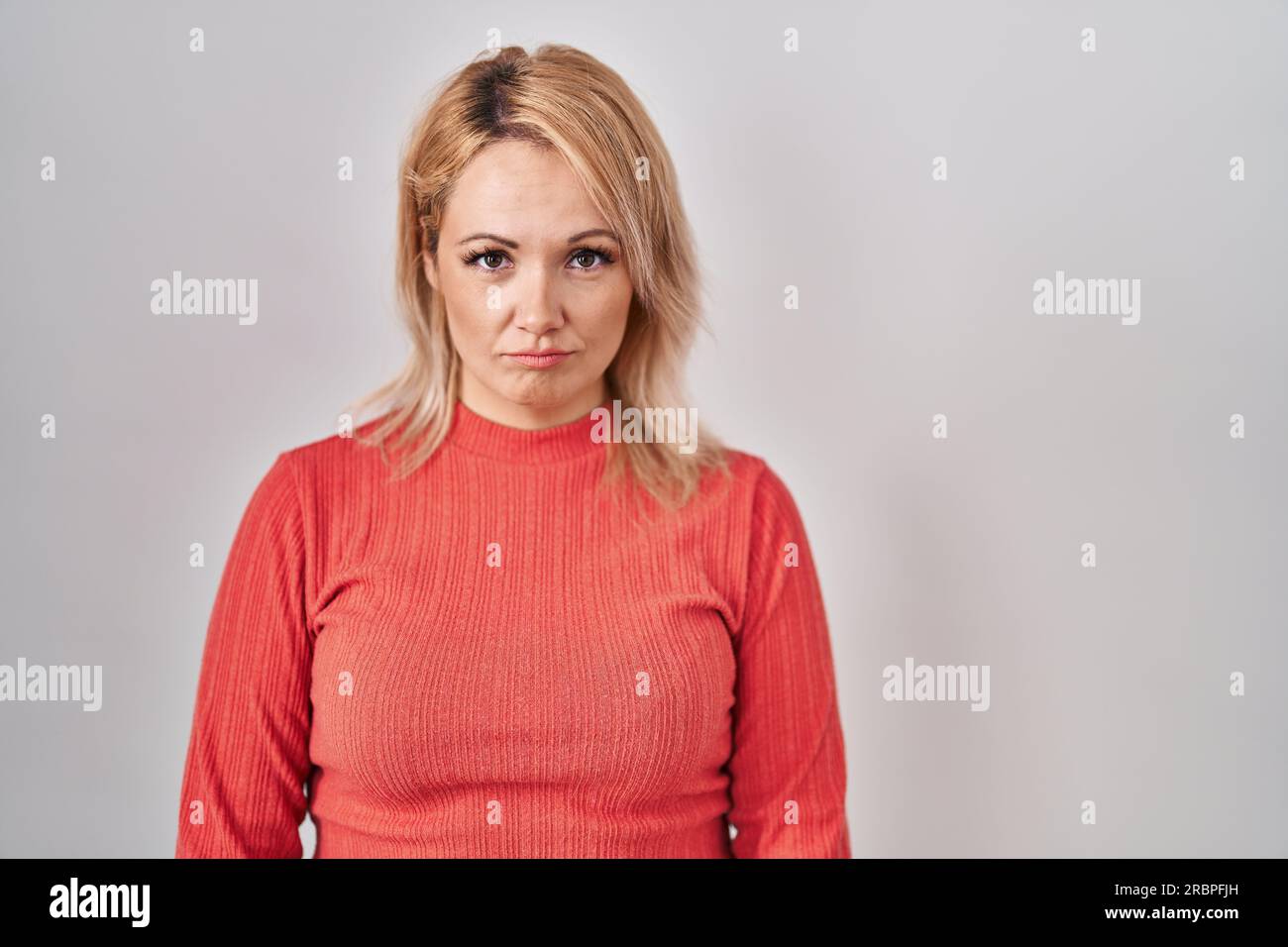 Blonde woman standing over isolated background depressed and worry for ...