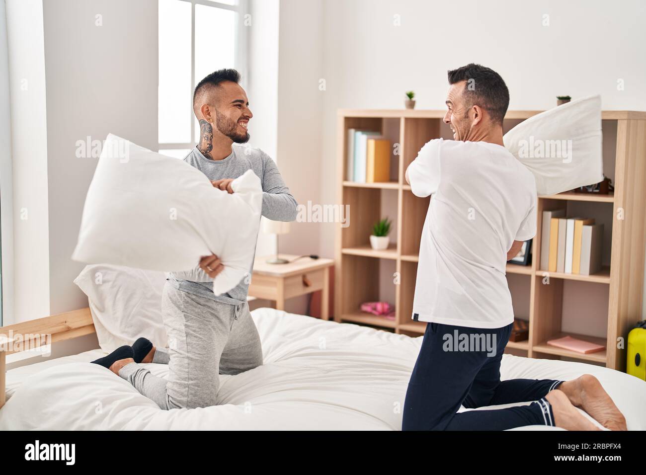 Two men couple fighting with pillows at bedroom Stock Photo - Alamy