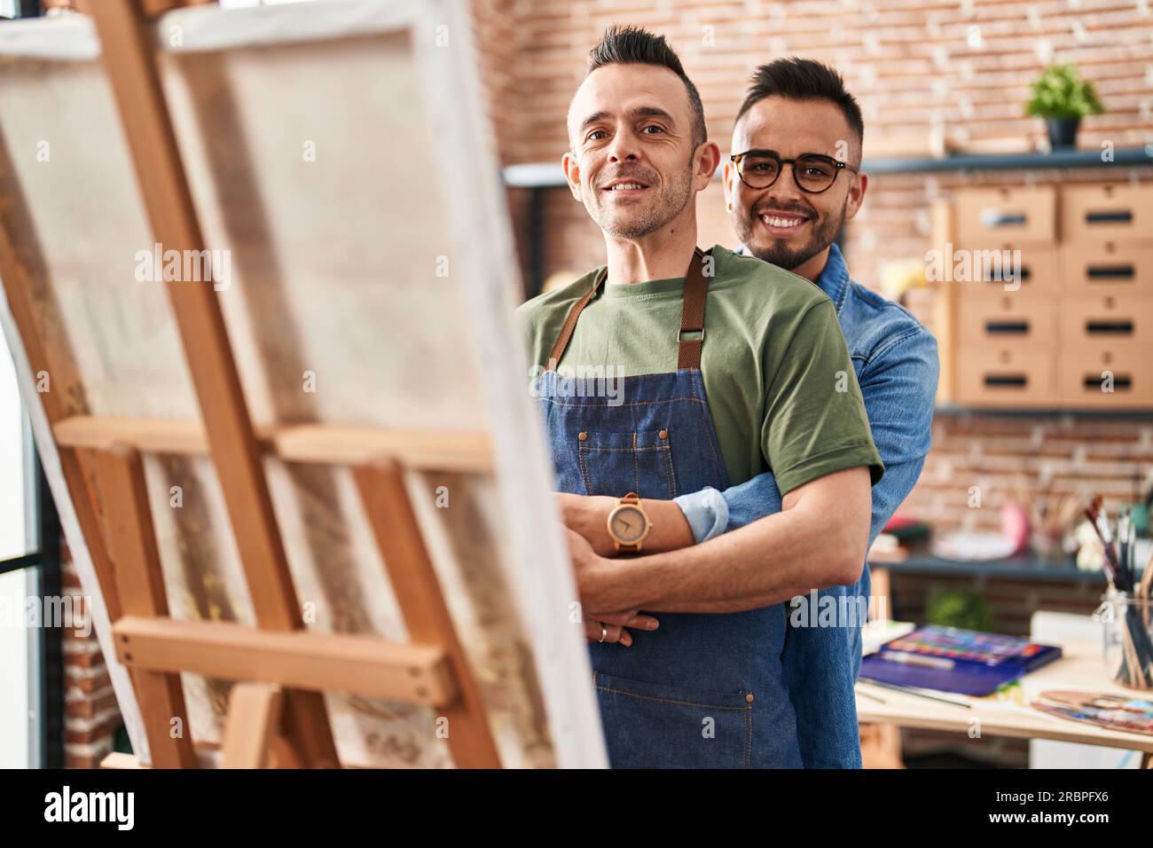 Two men artists hugging each other looking draw at art studio Stock ...