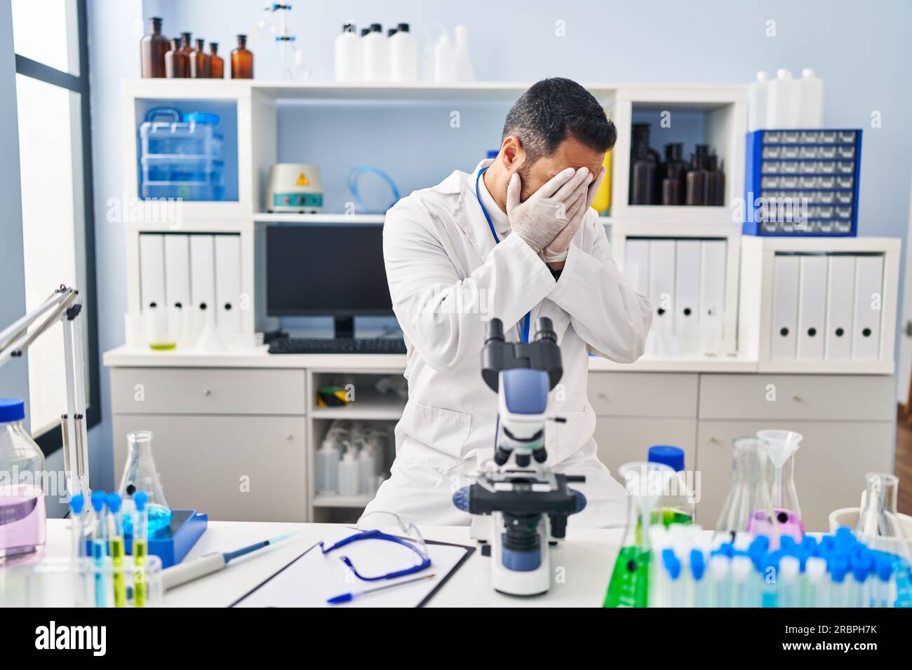 Young hispanic man with beard working at scientist laboratory with sad ...