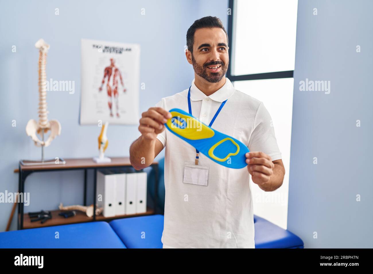 Young hispanic man podiatrist holding insole at podiatry center Stock ...