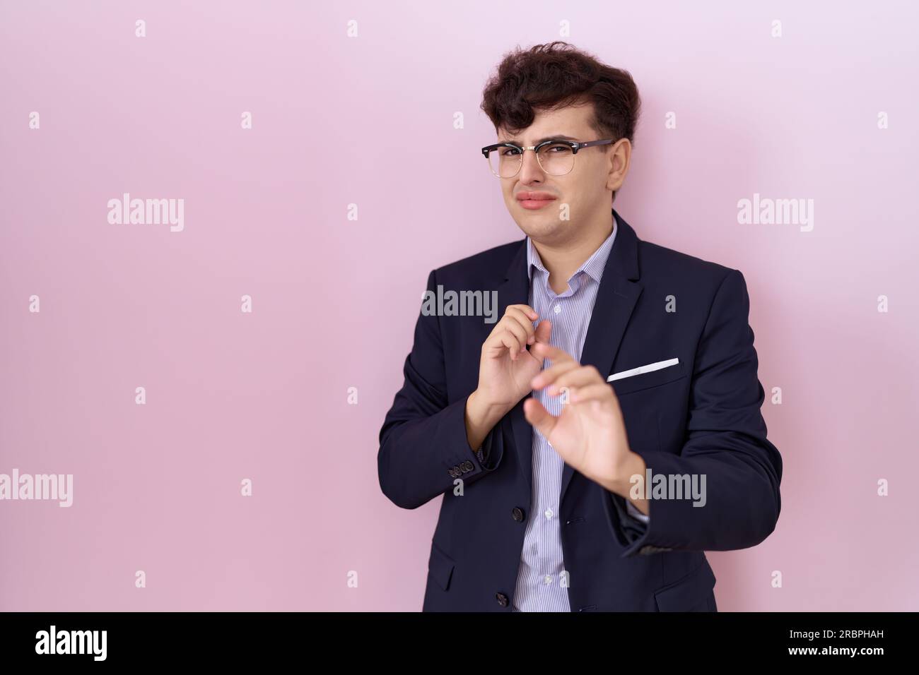 Young non binary man with beard wearing suit and tie disgusted ...