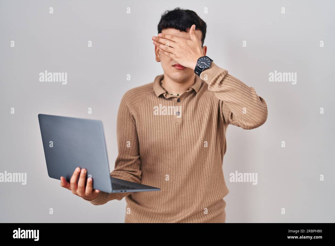 Non binary person using computer laptop covering eyes with hand ...