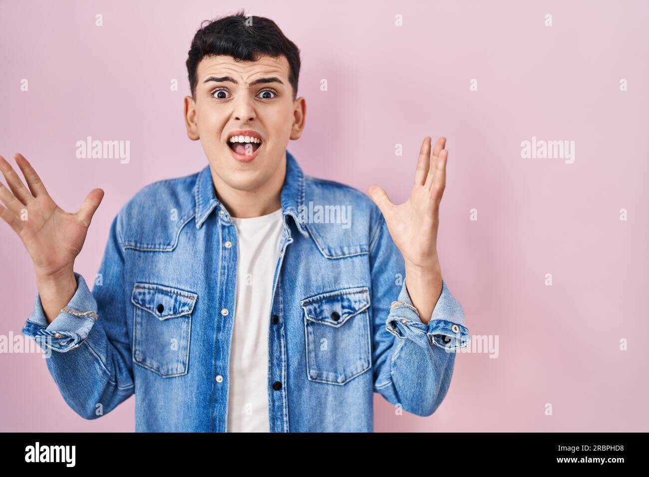 Non binary person standing over pink background celebrating victory ...