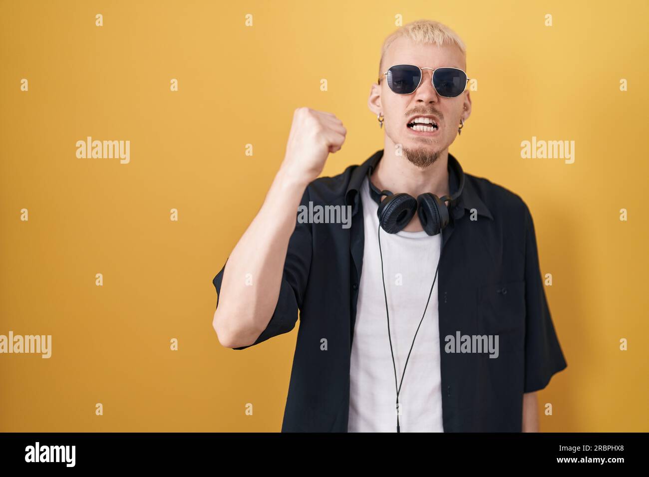 Young caucasian man wearing sunglasses standing over yellow background ...
