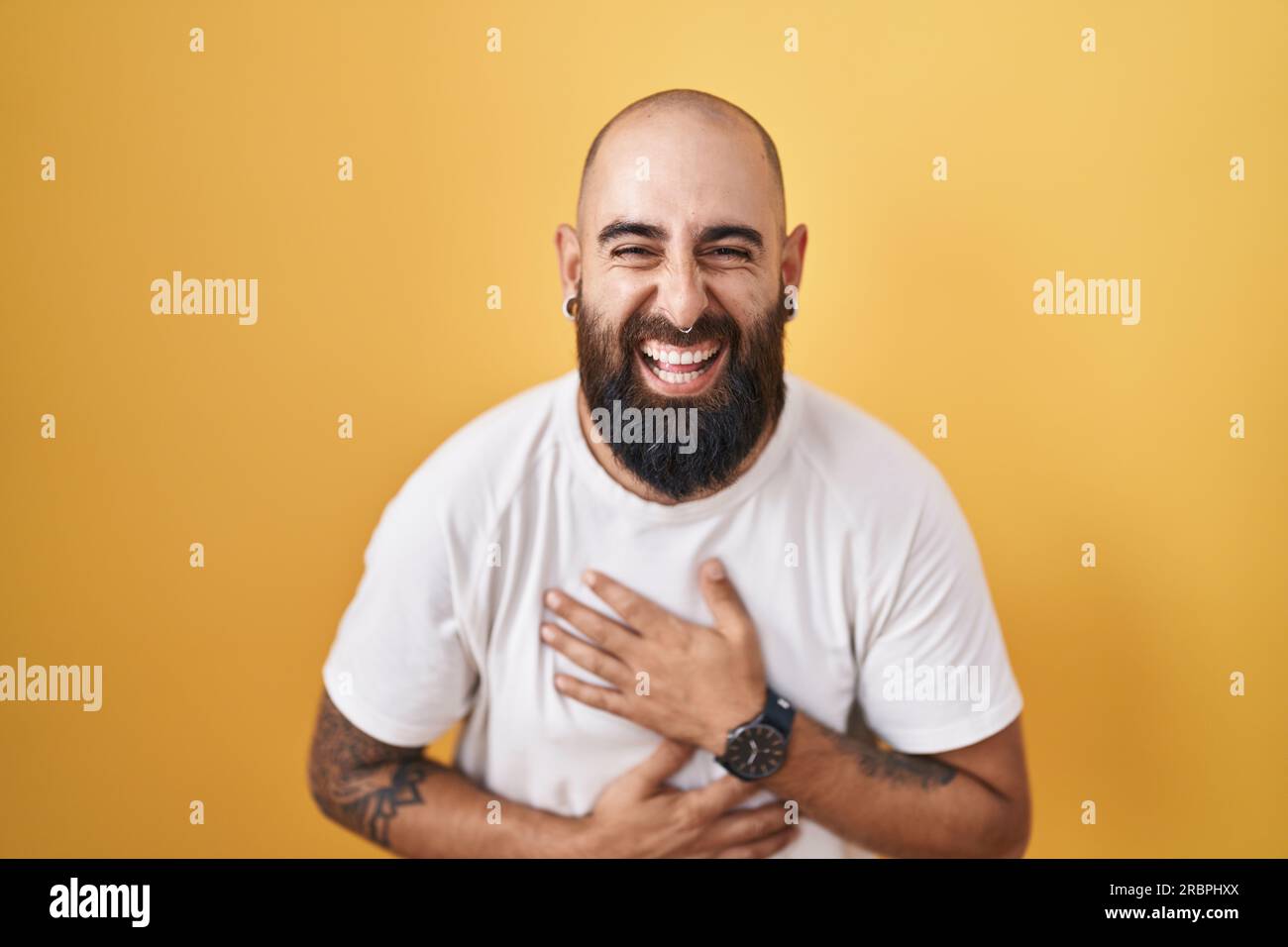 Young hispanic man with beard and tattoos standing over yellow ...