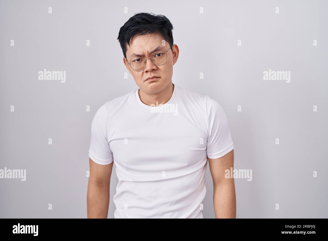 Young asian man standing over white background depressed and worry for ...