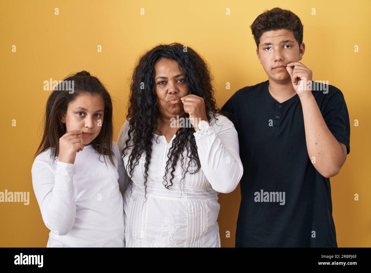 Family of mother, daughter and son standing over yellow background ...