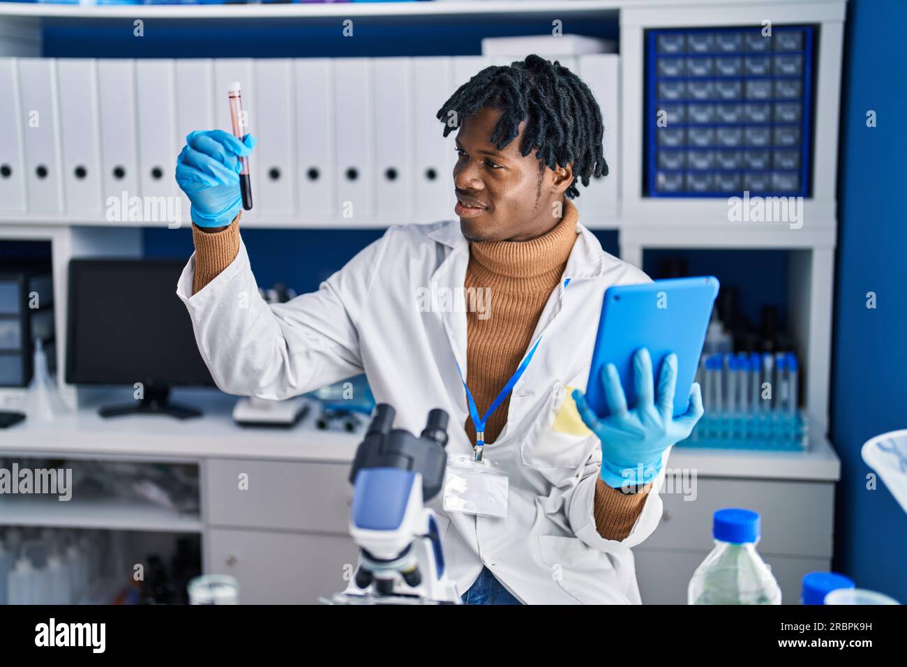 African american man scientist using touchpad holding test tube at ...