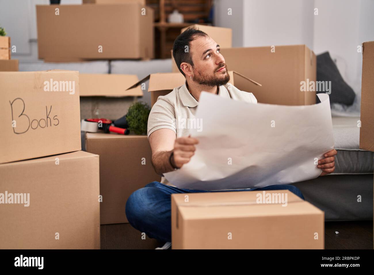 Young hispanic man looking house plans at new home Stock Photo - Alamy