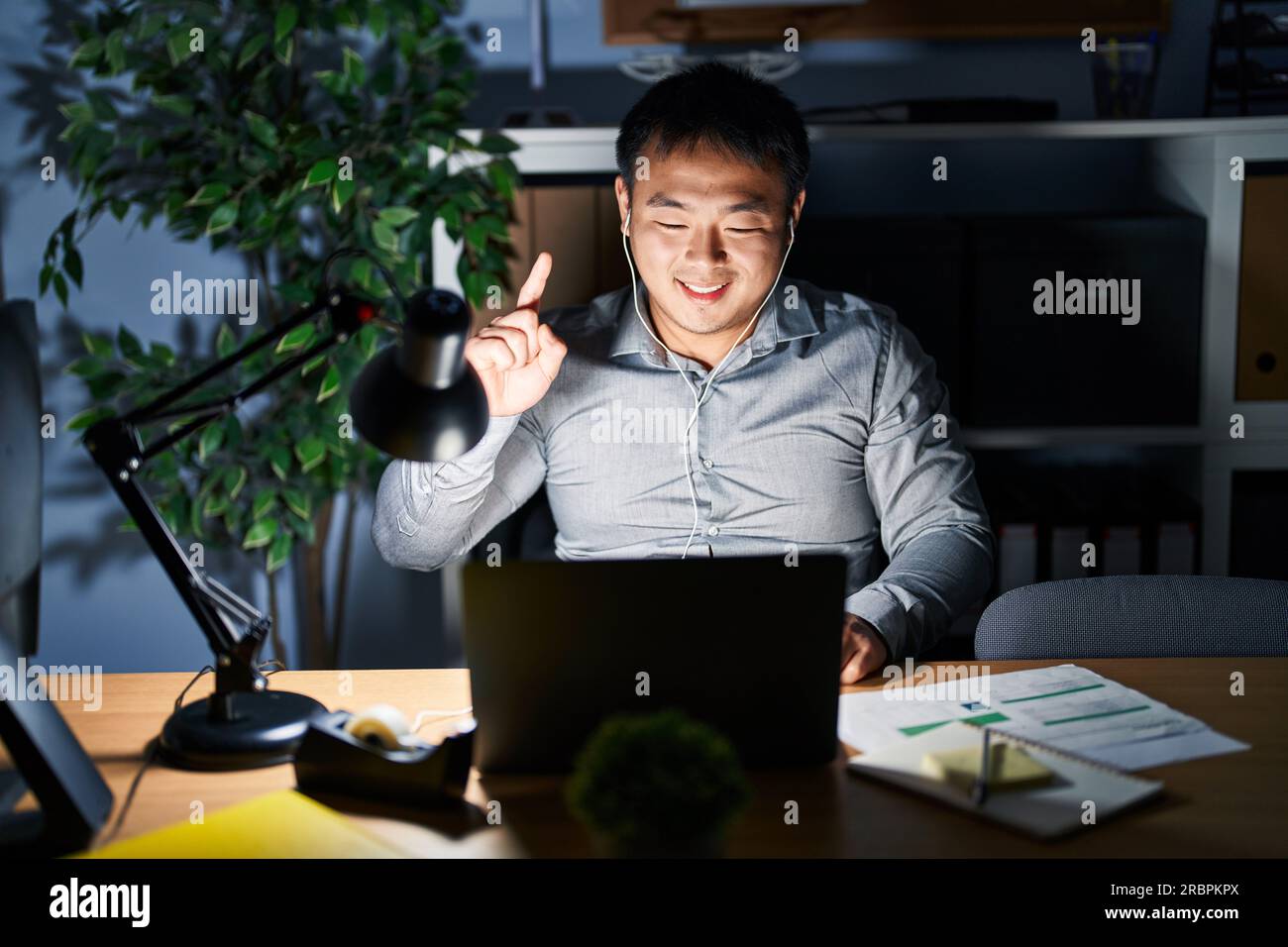 Young chinese man working using computer laptop at night showing and ...