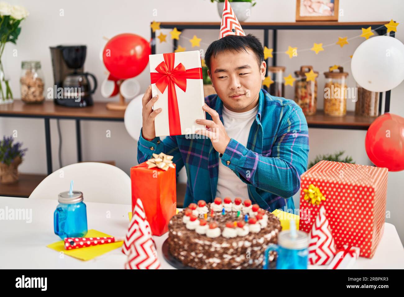 Young chinese man celebrating birthday holding gift at home Stock Photo ...