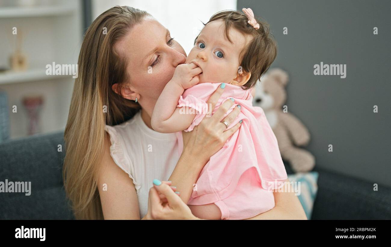 Mother and daughter hugging each other sitting on sofa kissing at home Stock Photo - Alamy