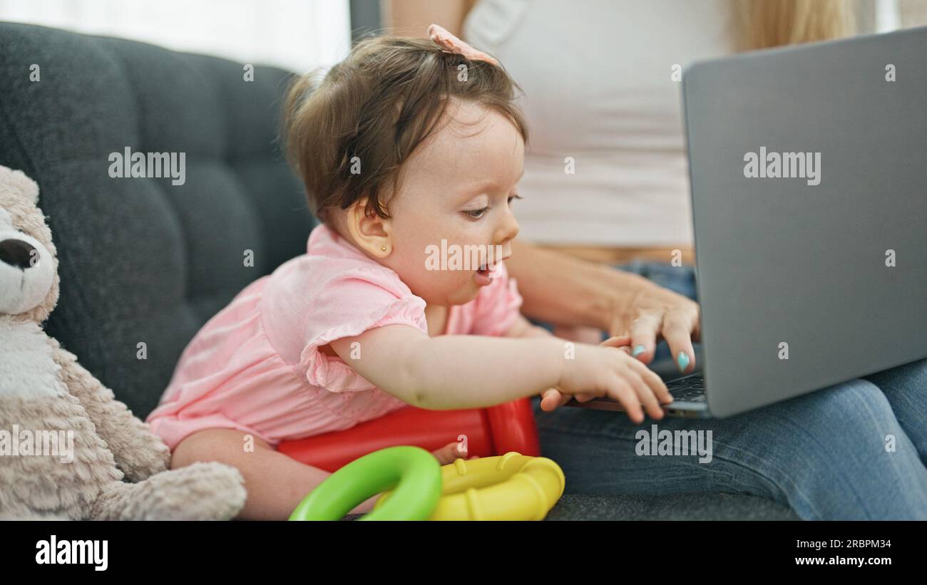 Mother and daughter using laptop while playing with hoops at home Stock ...