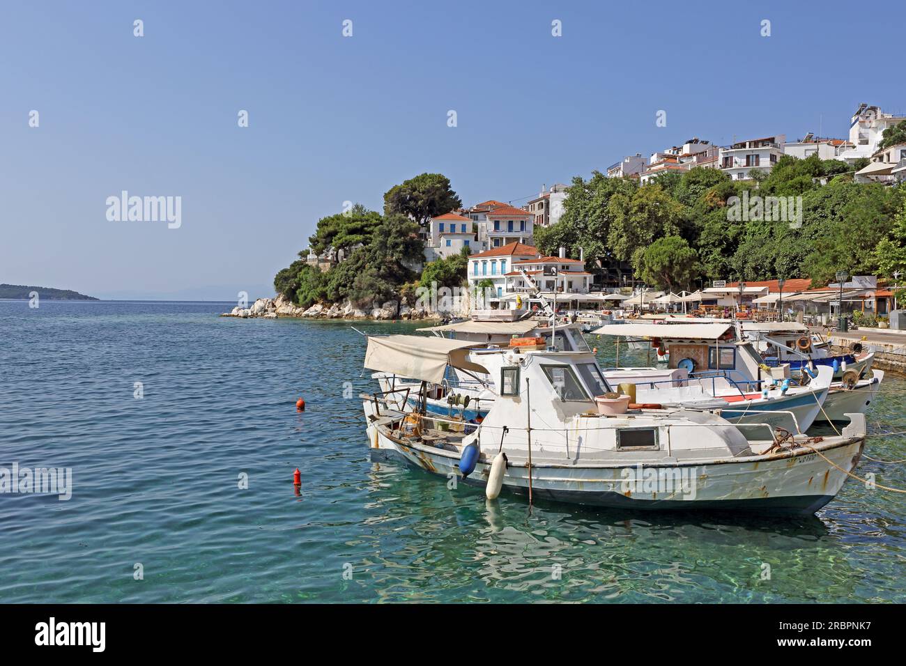 View from the fishing boats at the harbor quay of Skiathos town ...