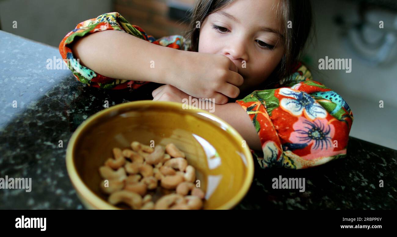 Little girl eating cashew nuts from bowl child eats healthy snack food ...