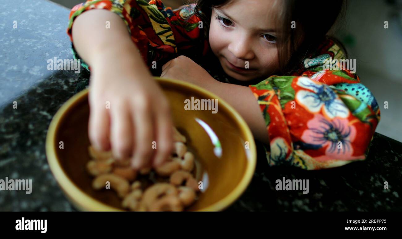 Little girl eating cashew nuts from bowl child eats healthy snack food ...