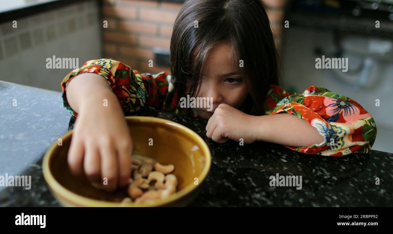 Little girl grabbing cashew nuts from bowl kid eating healthy snack ...
