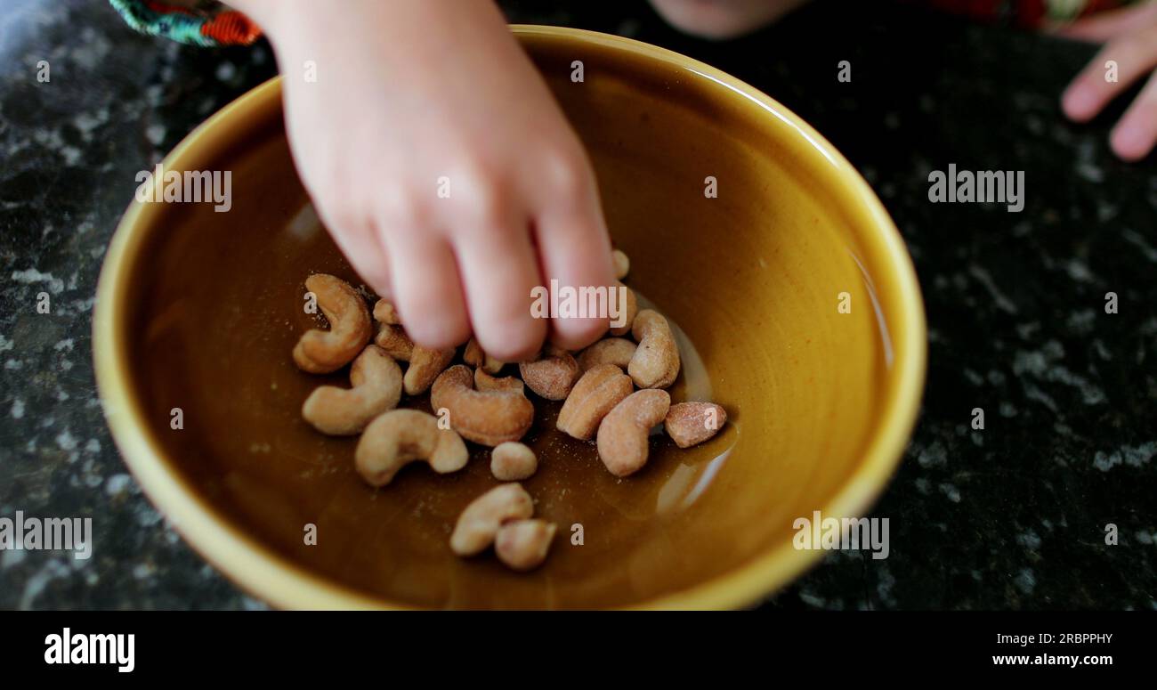 Child eating cashew nuts from bowl Stock Photo - Alamy