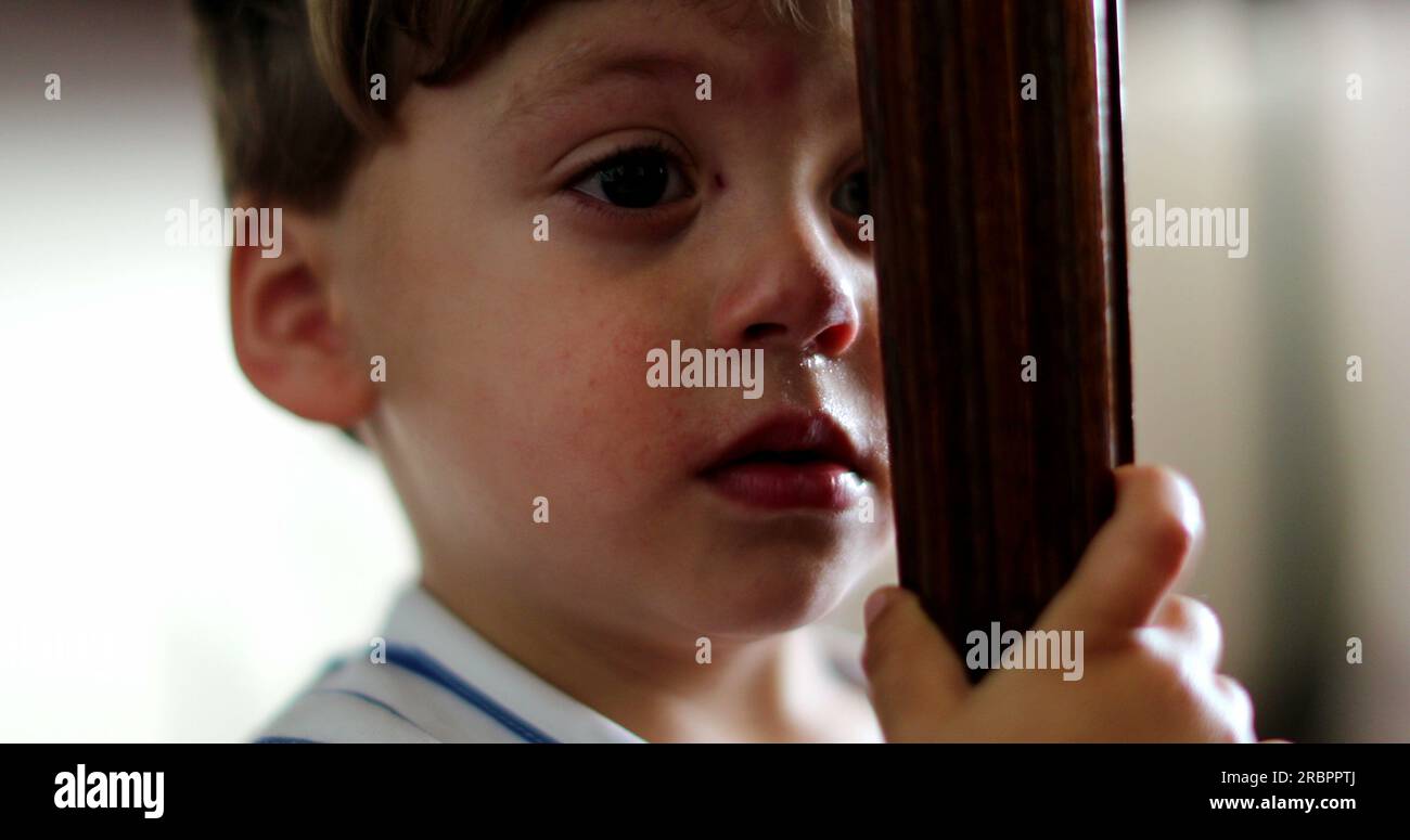 Fearful child hiding behind furniture feeling scared kid being afraid ...