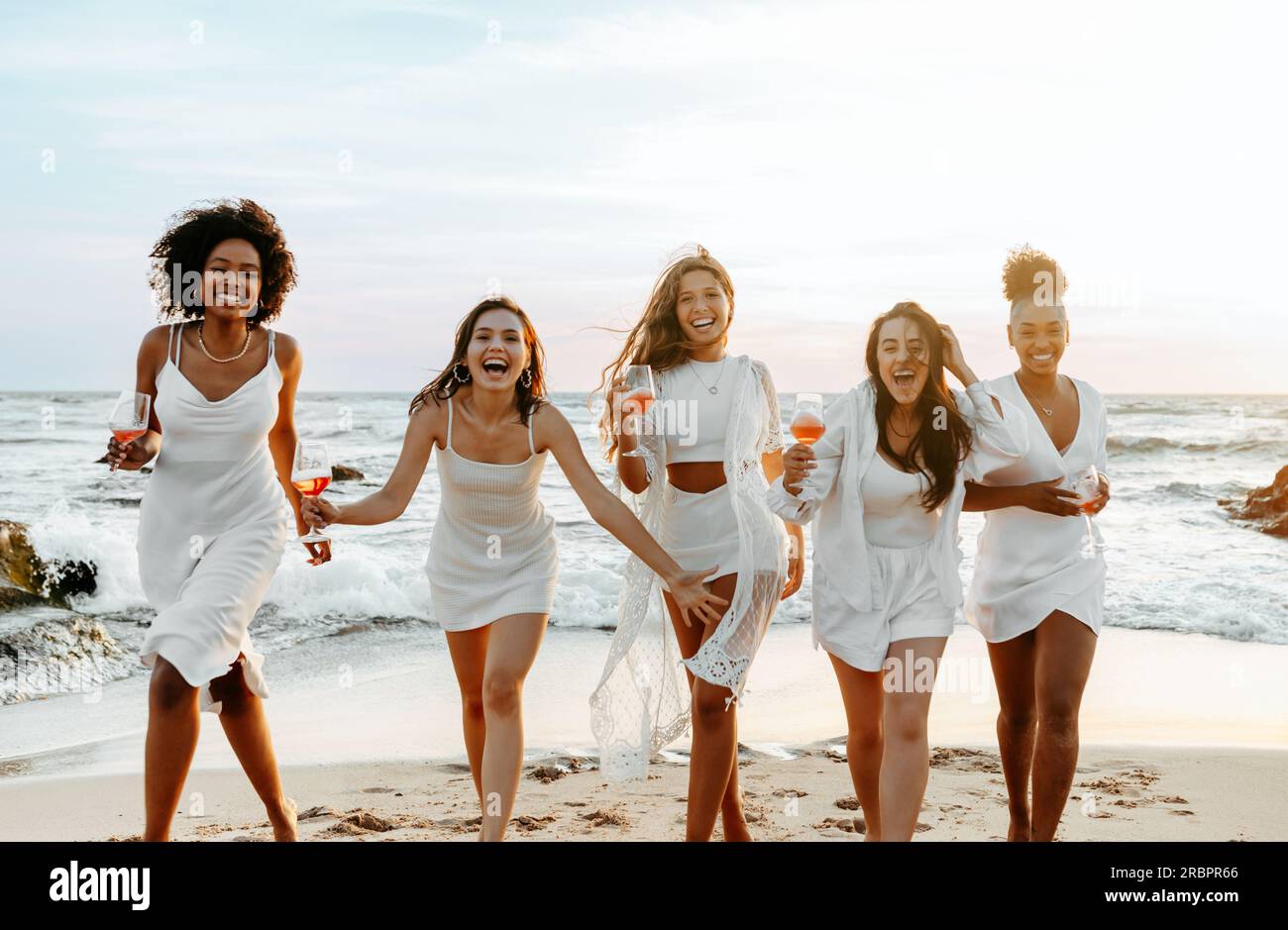 Bride's team. Group of happy ladies dancing and having fun on the beach ...