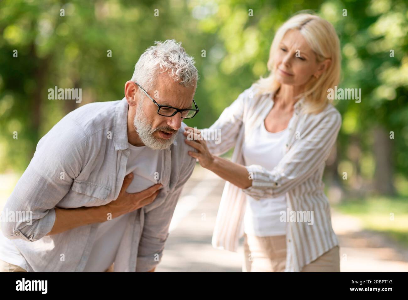 Senior man suffering from heart attack while walking with wife in park ...