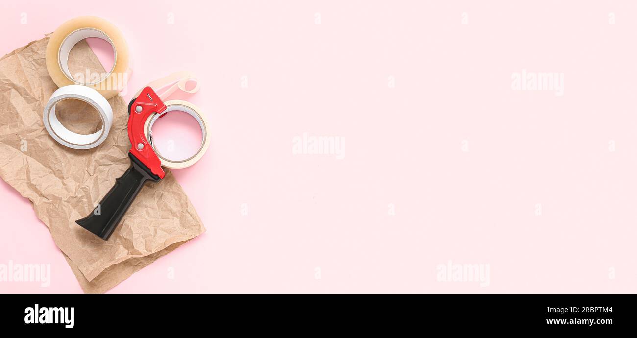 Adhesive tape rolls, dispenser and wrapping paper on pink background ...
