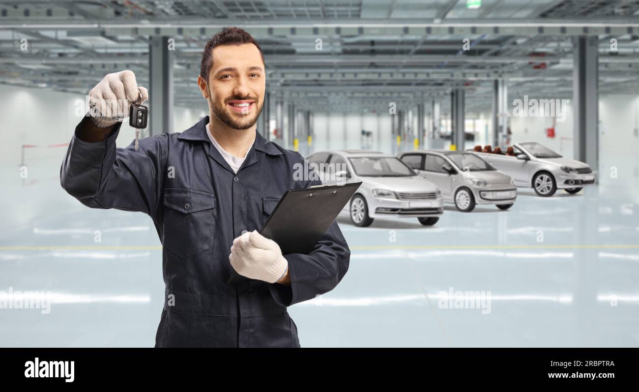 Auto mechanic with a car key and a clibboard standing inside a garage ...