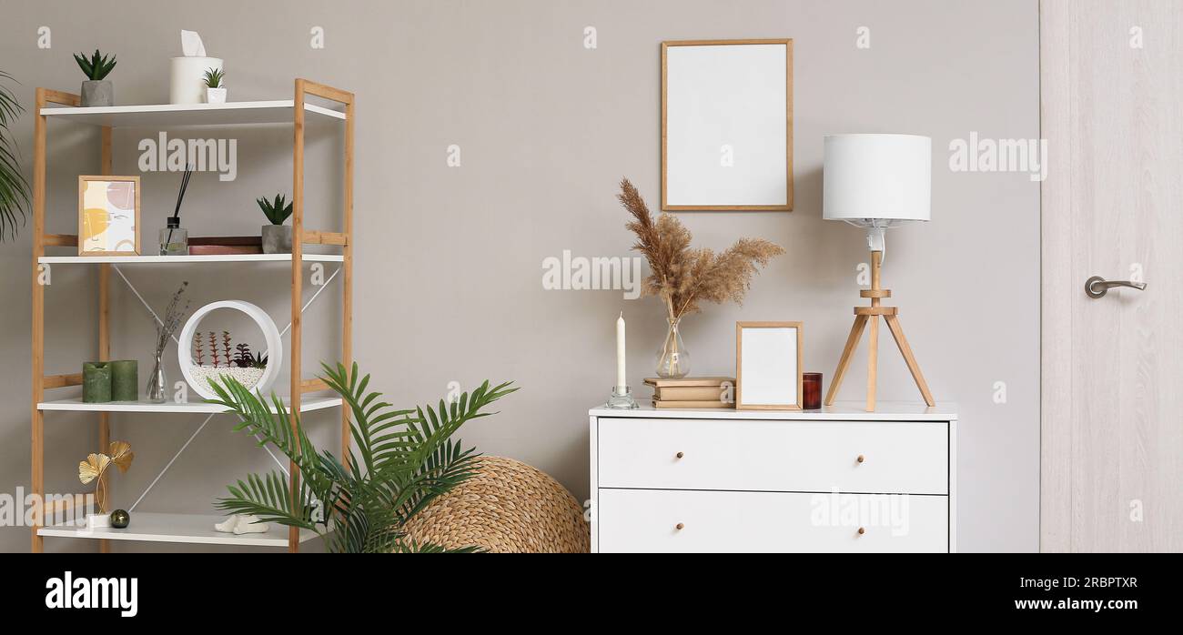 Interior of modern room with blank frames, chest of drawers and ...