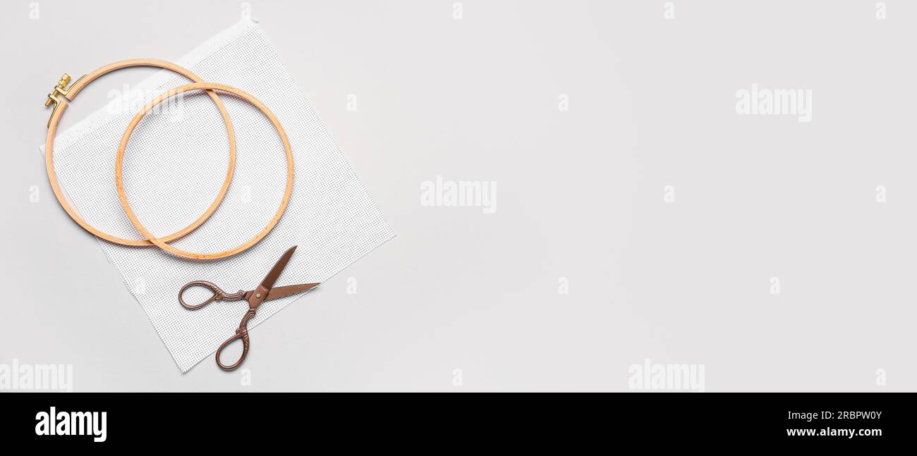 Wooden embroidery hoops with canvas and scissors on light background ...